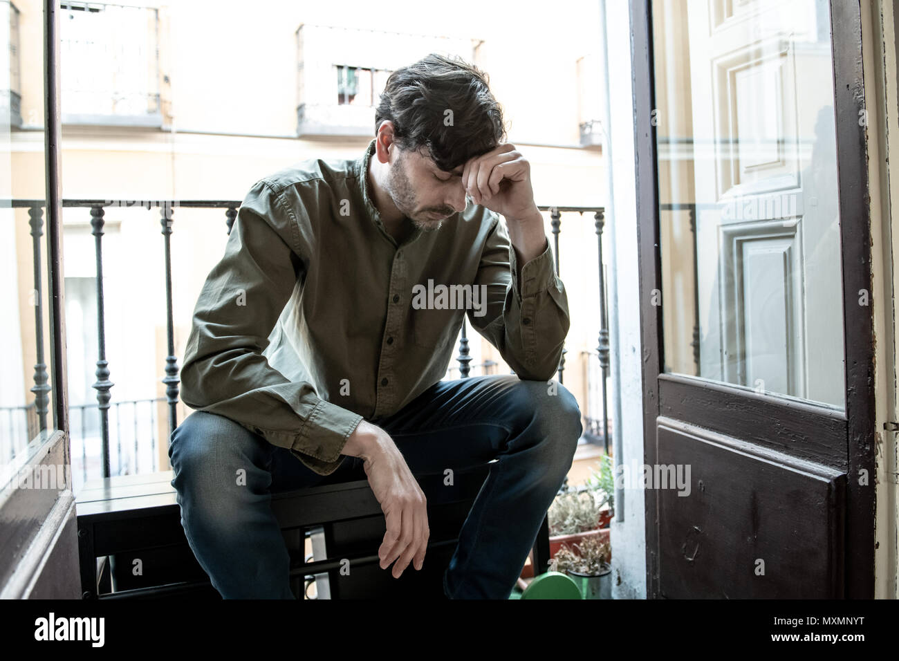 Lonely young man looking outside house balcony looking depressed ...