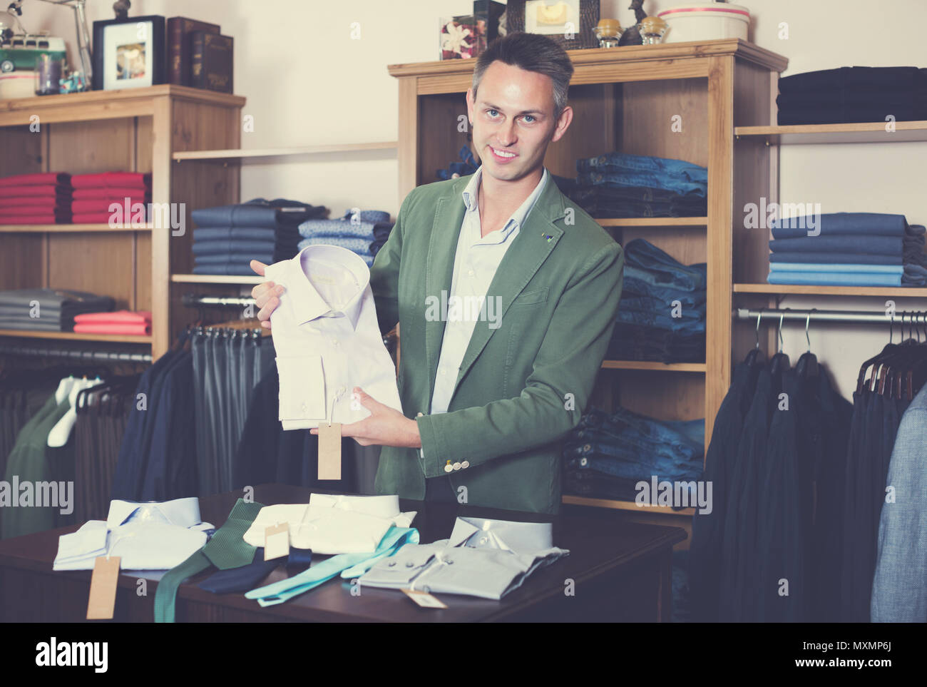 Male shopping assistant offering various cloths in store Stock Photo ...