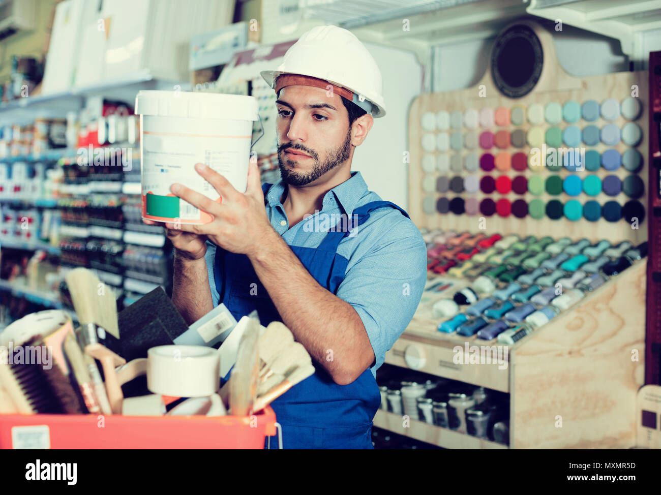 Serious foreman closely reading instruction on paint at hardware store ...