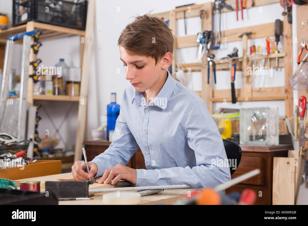cheerful american teenager smiling and working with wood in the ...