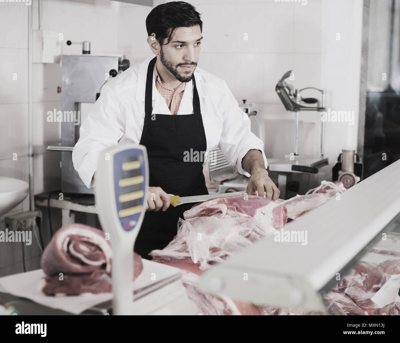 Joyful butcher is cutting meat for clients in market Stock Photo - Alamy Joyful butcher is cutting meat for clients in market Stock Photo - Alamy