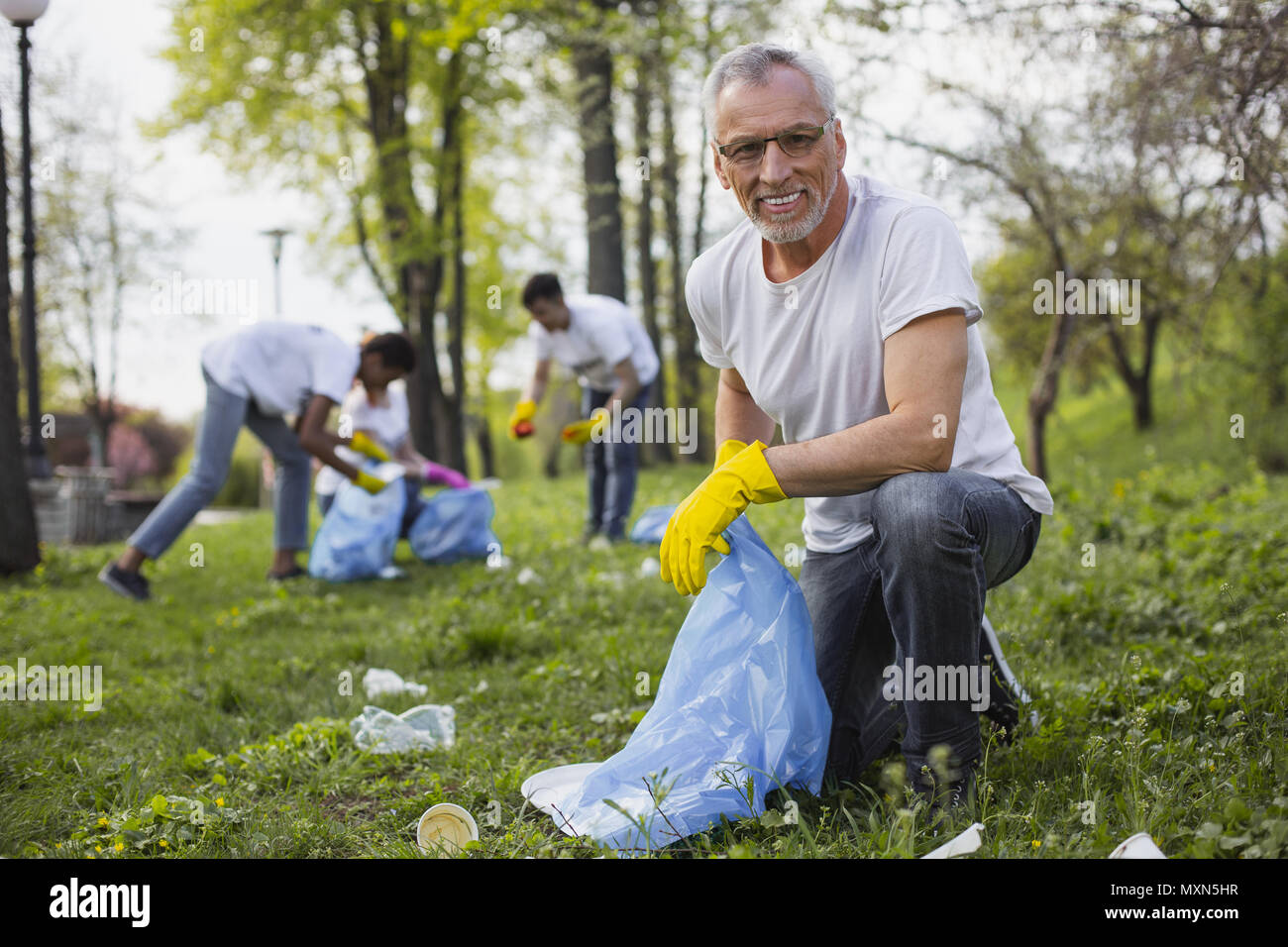 Happy senior volunteer gathering trash Stock Photo - Alamy