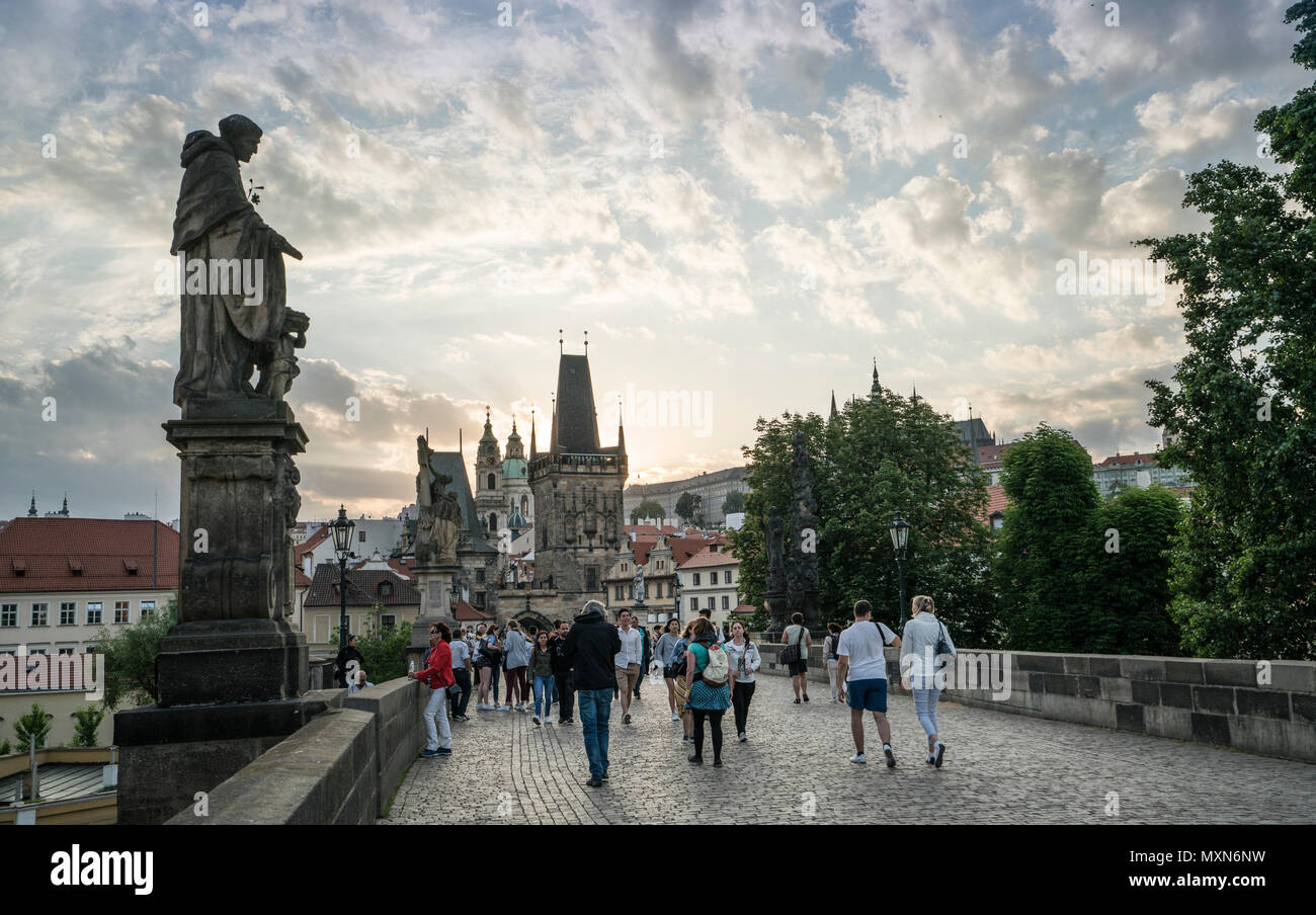 Tourists walk on Charles bridge at sunset in Prague, Czech Republic ...