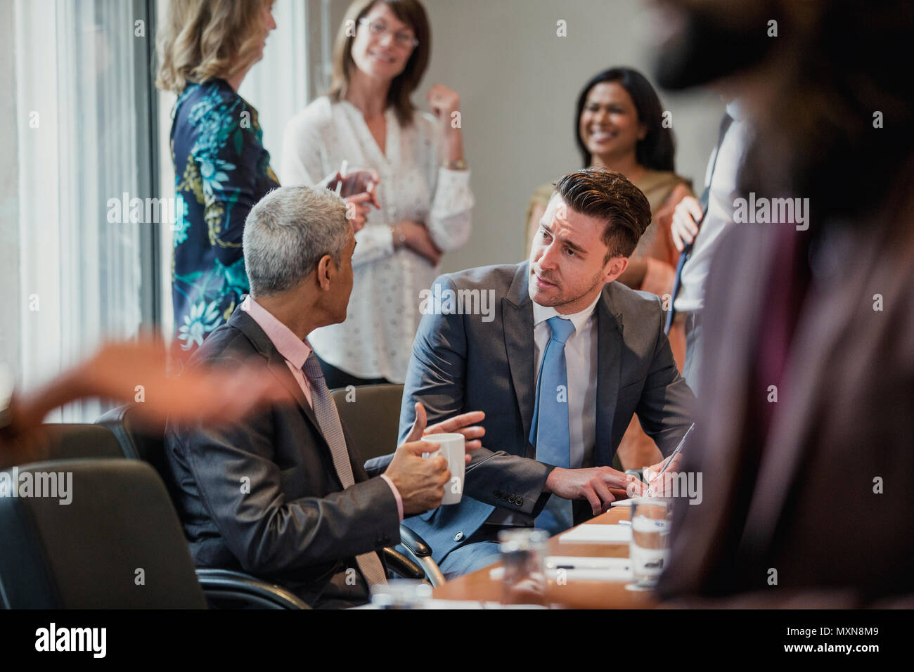 Two male businessmen talking during a conference. One businessman is ...