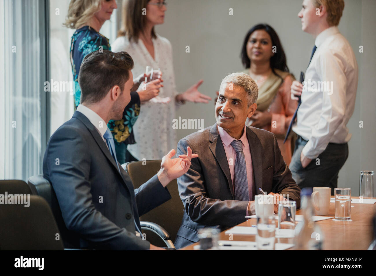 Two male businessmen having a conversation while sat at the conference ...