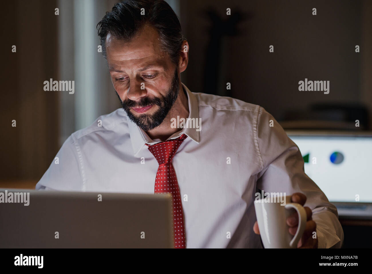 Front view of a businessman working late in the office to get his work ...