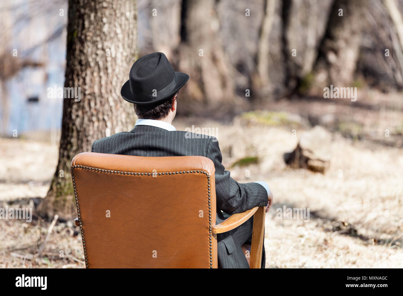 man alone in the woods sitting on a vintage armchair, rear view Stock ...