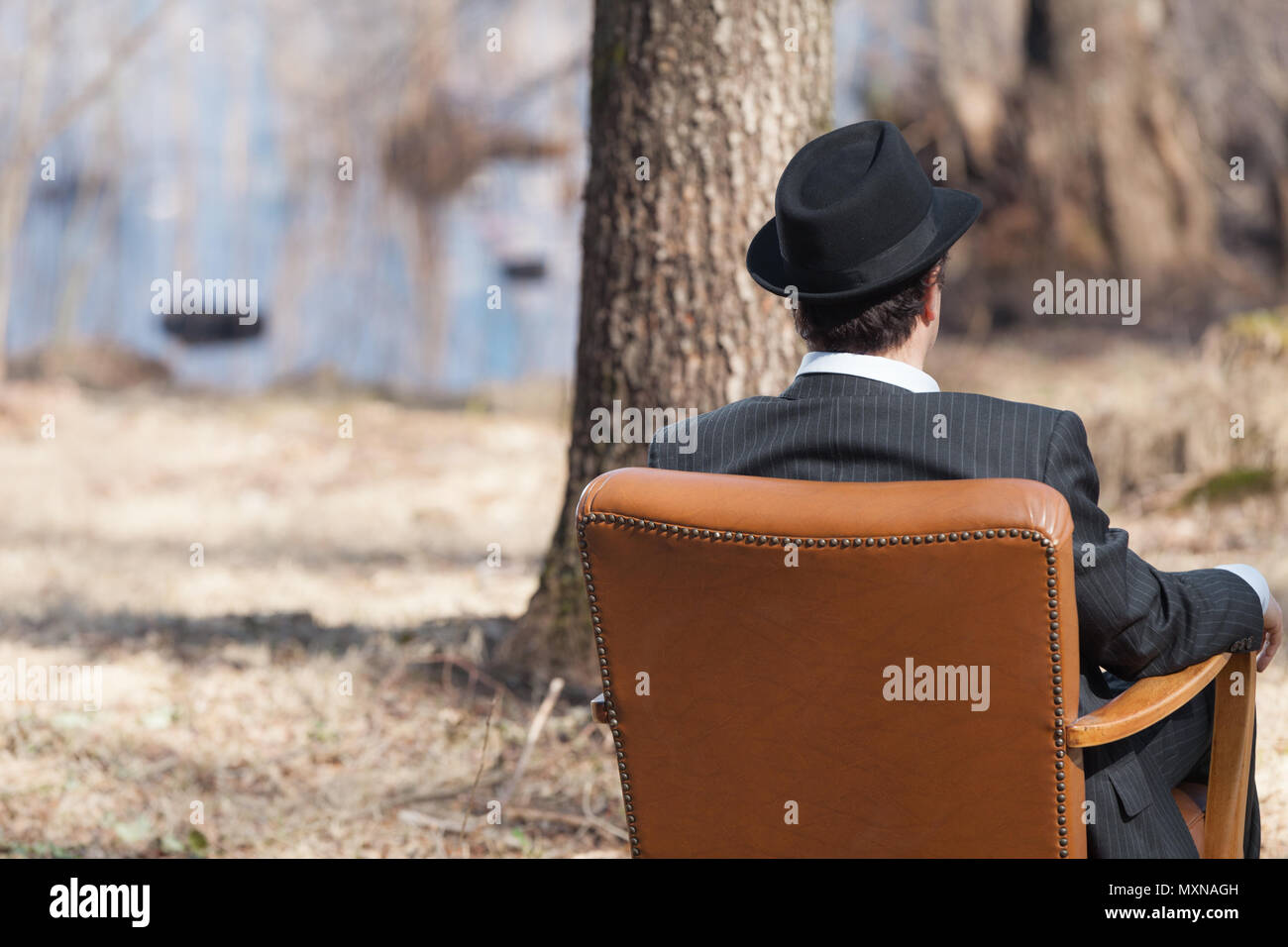 man alone in the woods sitting on a armchair, rear view Stock Photo - Alamy