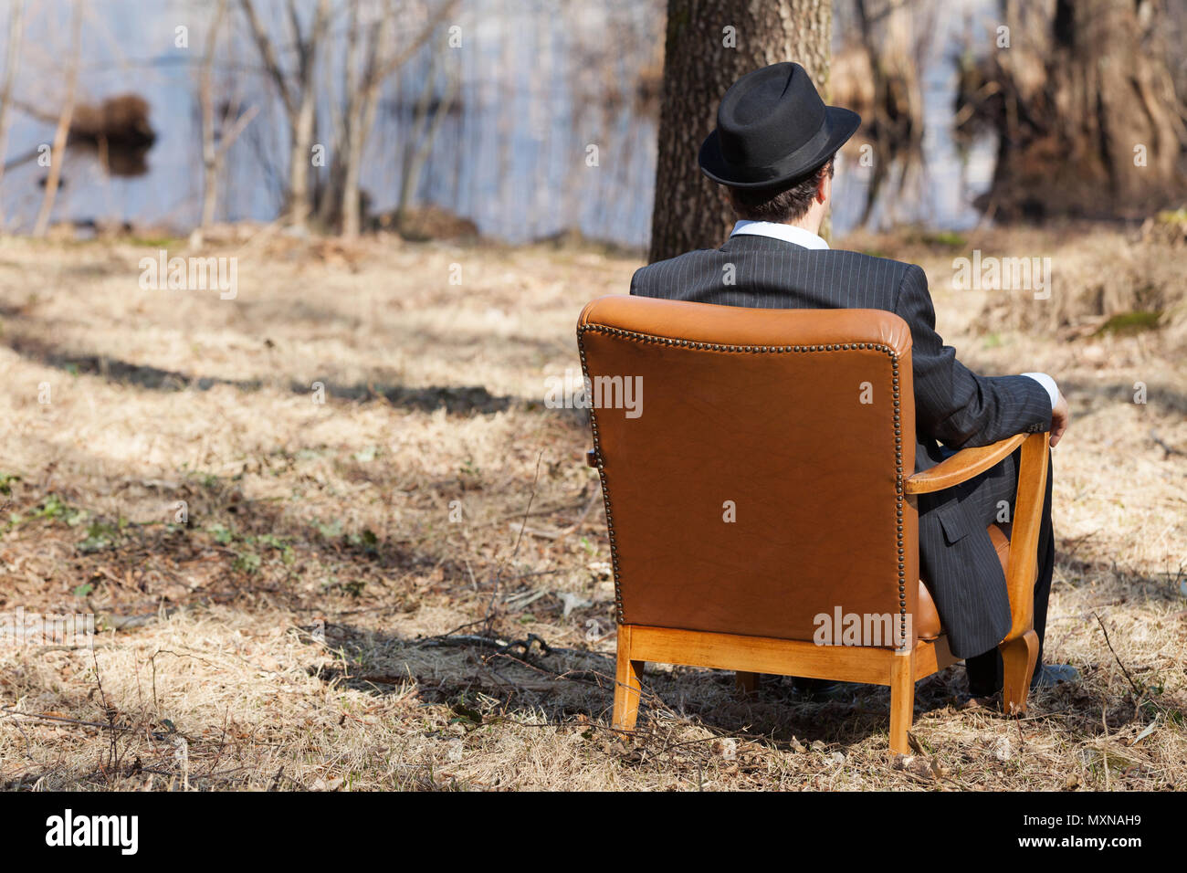 man alone in the woods sitting on a vintage armchair, rear view Stock ...