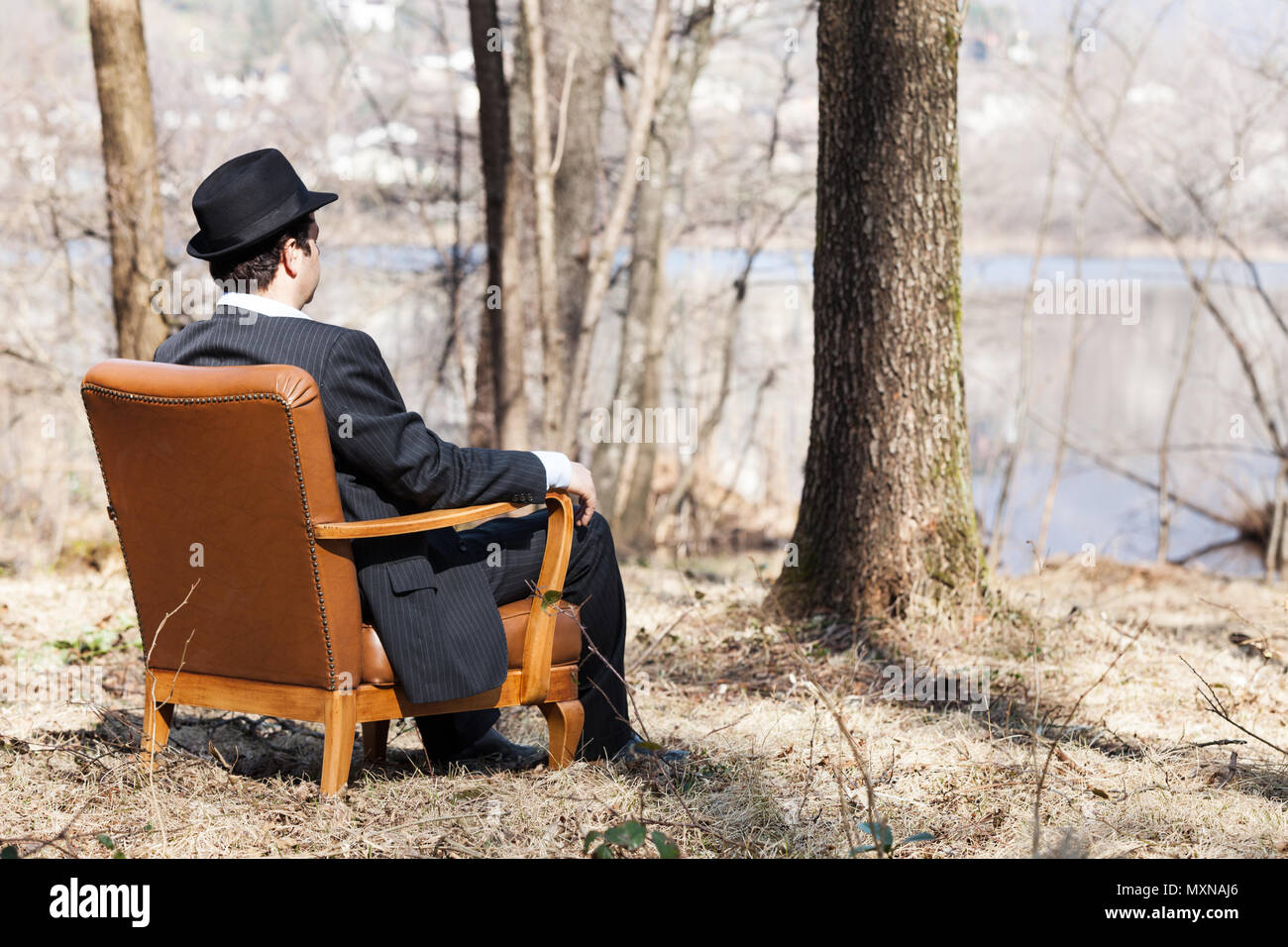 man alone in the woods sitting on a vintage armchair, rear view Stock ...