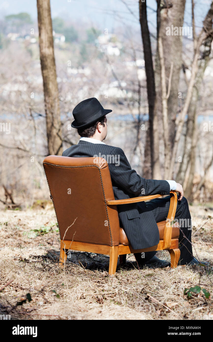man alone in the woods sitting on a vintage armchair, rear view Stock ...