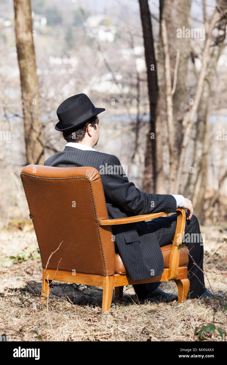 man alone in the woods sitting on a vintage armchair, rear view Stock ...