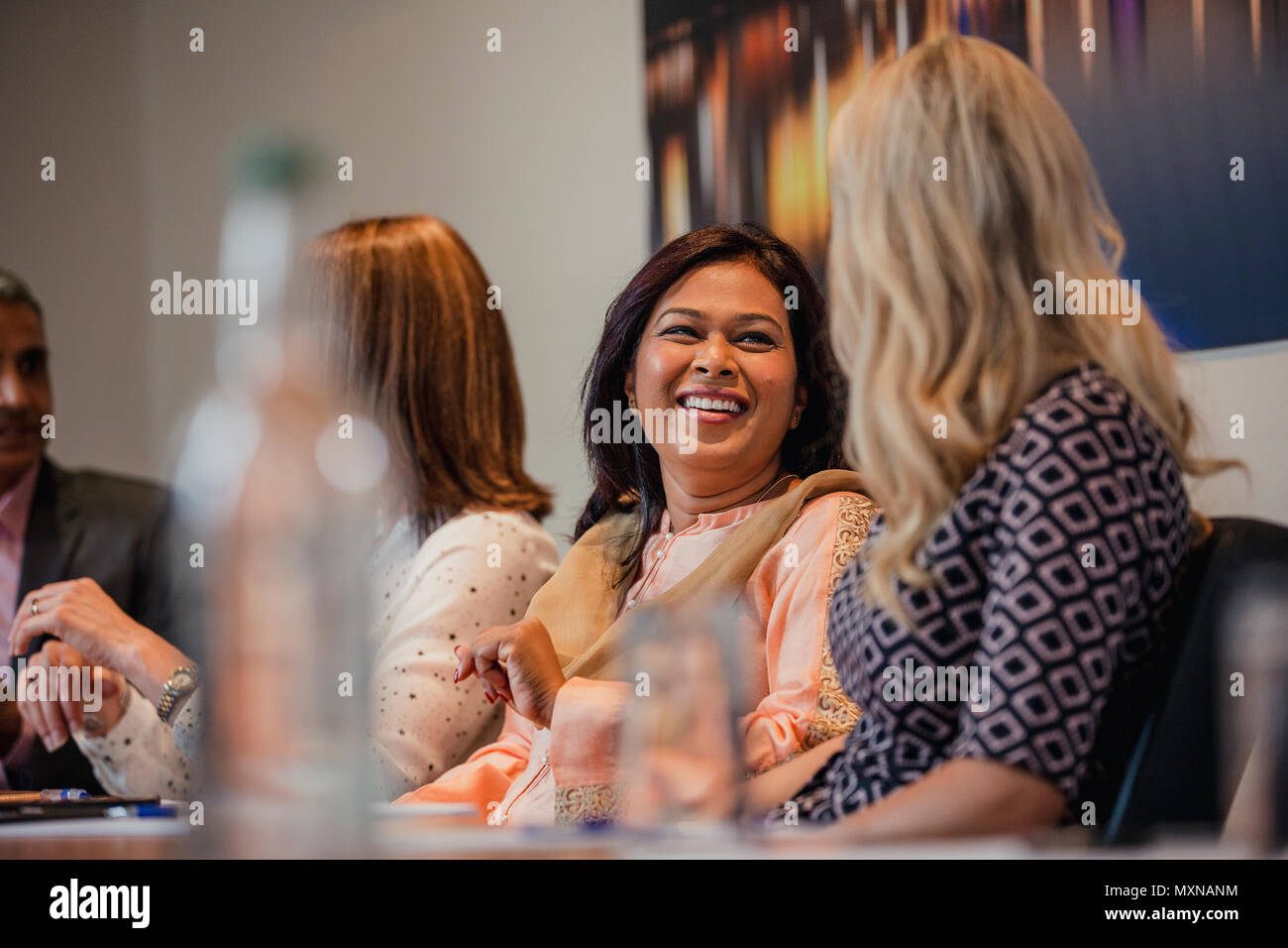 Two businesswomen talking while sitting down at a conference table ...