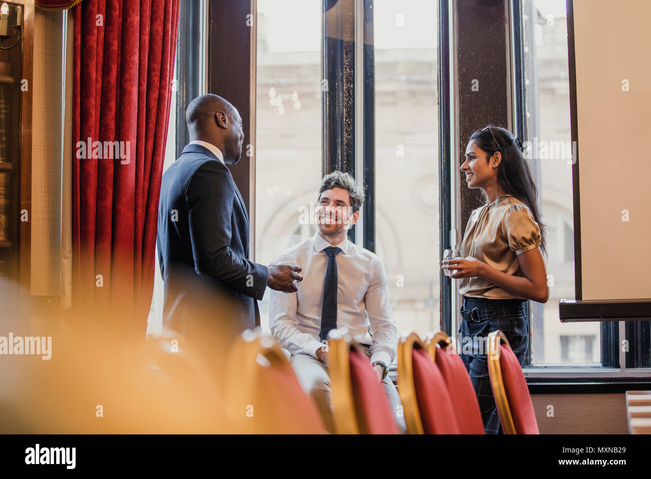Side view of three business people, standing, talking after a business ...