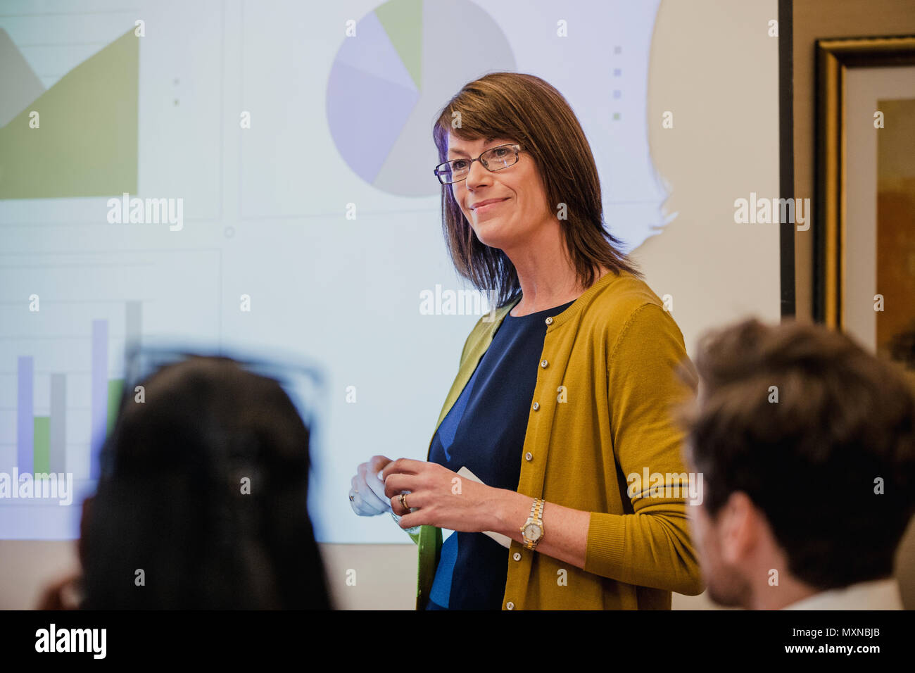 Rear view, close-up of business people listening to a presenter at a ...