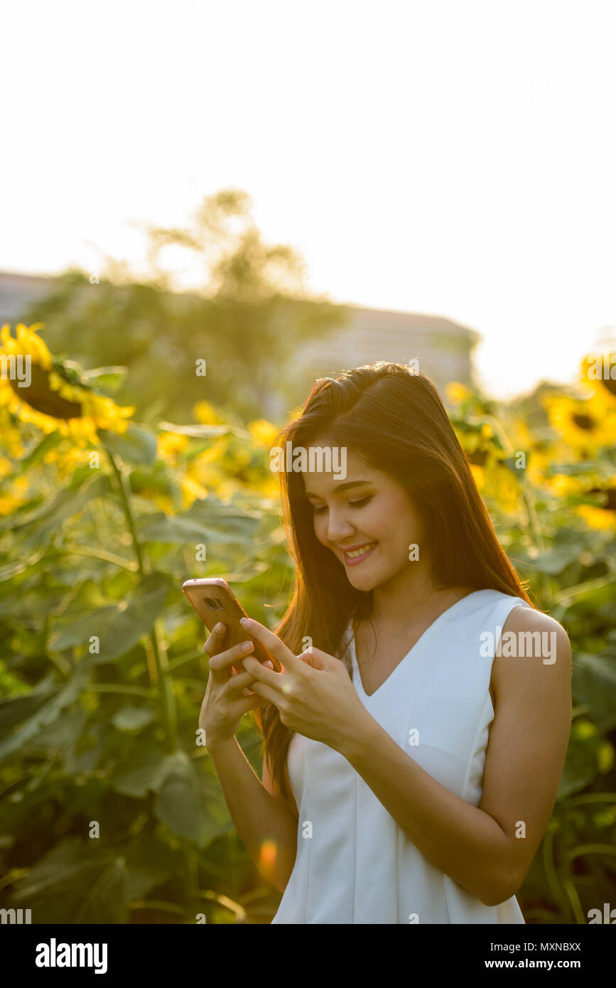 Young happy Asian woman smiling while using mobile phone in the Stock ...