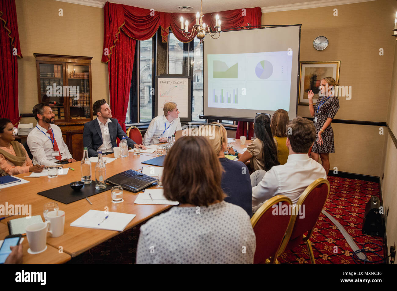Rear view of a large group of people lookig towards a businesswoman ...