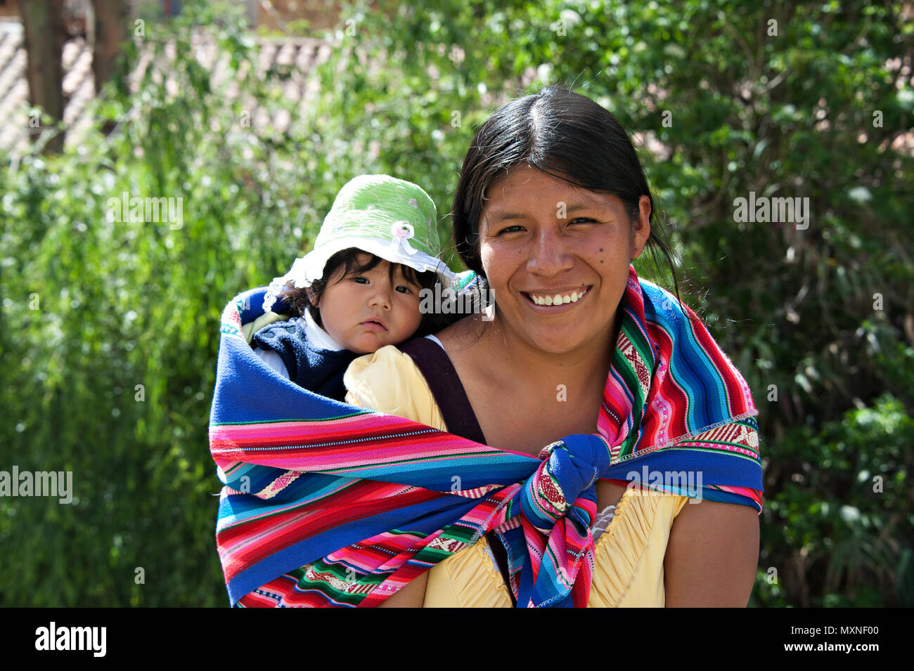 Local villager woman in traditional coloured shawl carrying her child ...