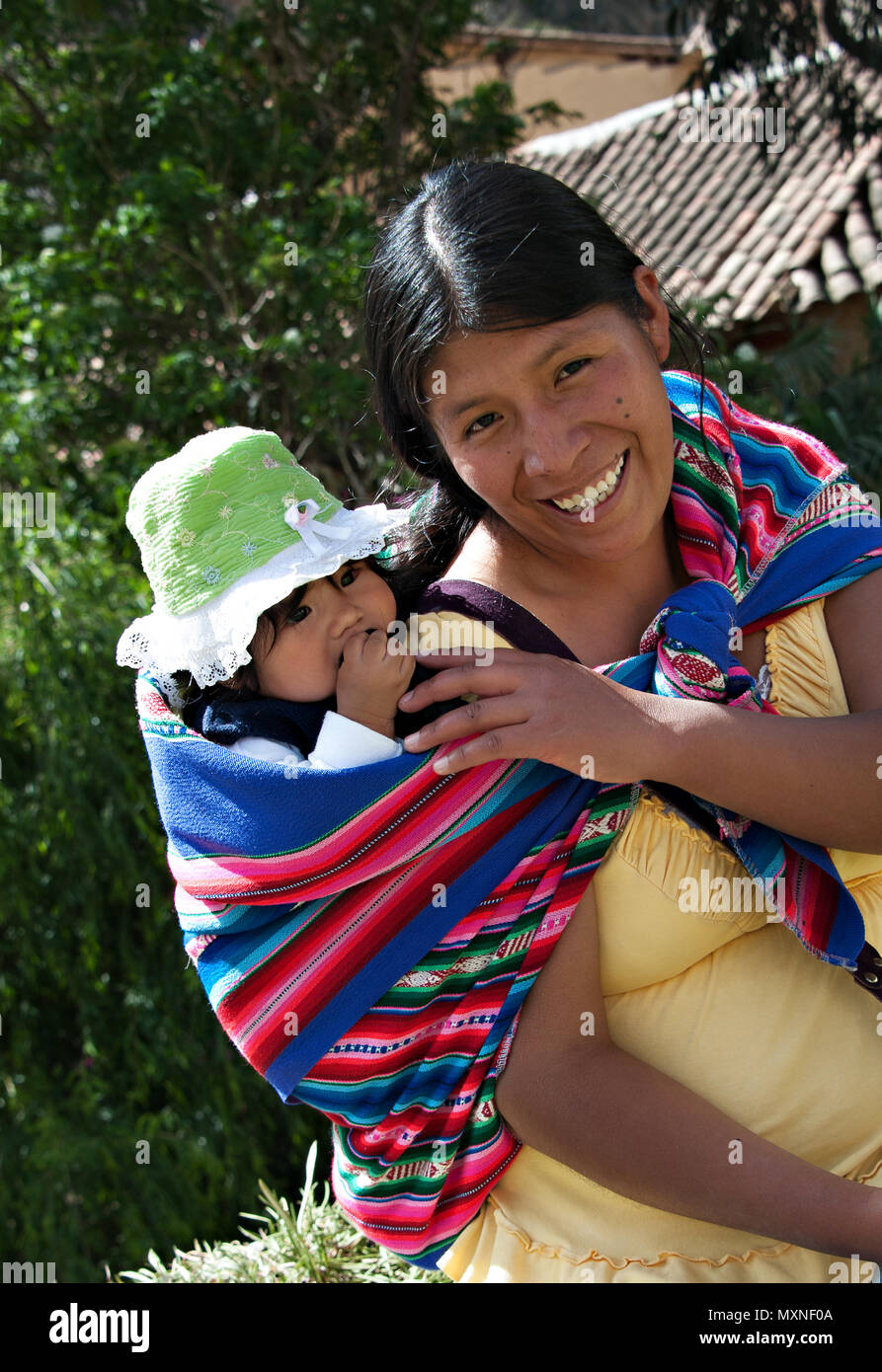 Local villager woman in traditional coloured shawl carrying her child ...