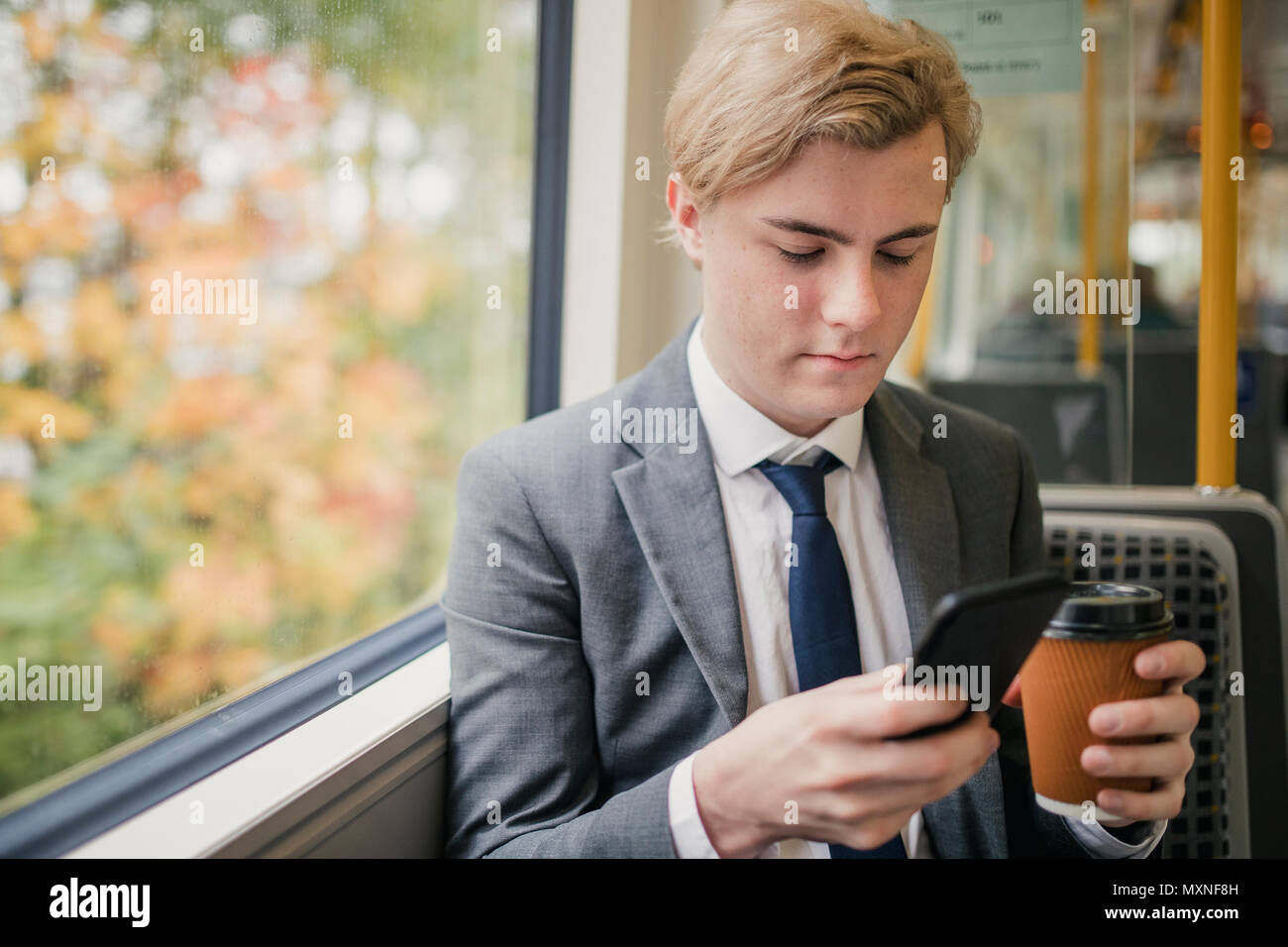 Young businessman using his smart phone while on his commute to work on ...