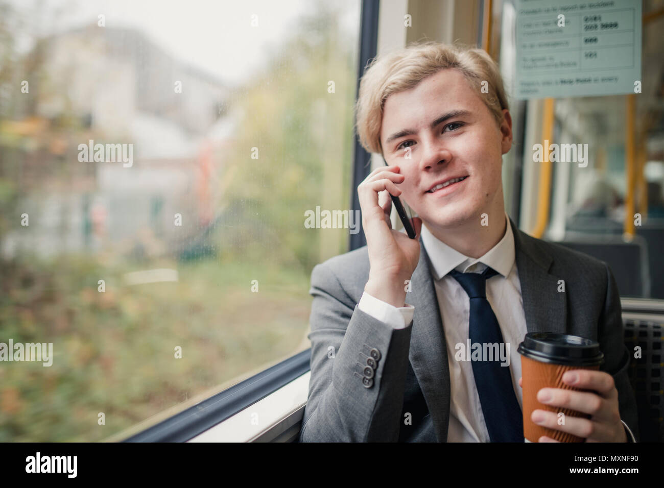 Young businessman making a phone call on the train on his commute to ...
