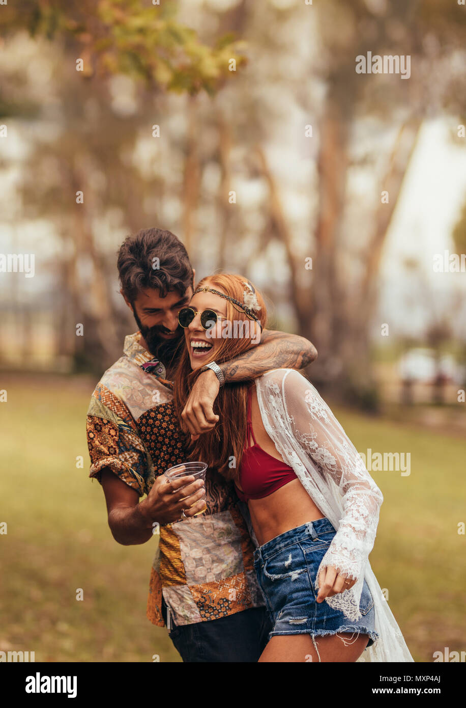 Hippie couple having fun at music festival. Man with a glass of beer ...