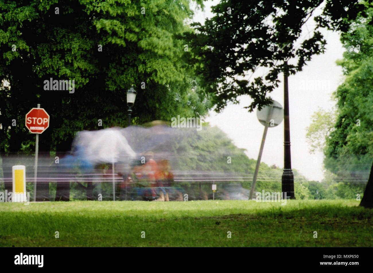 Family with a pushchair in front of a Stop sign crossing a road in ...
