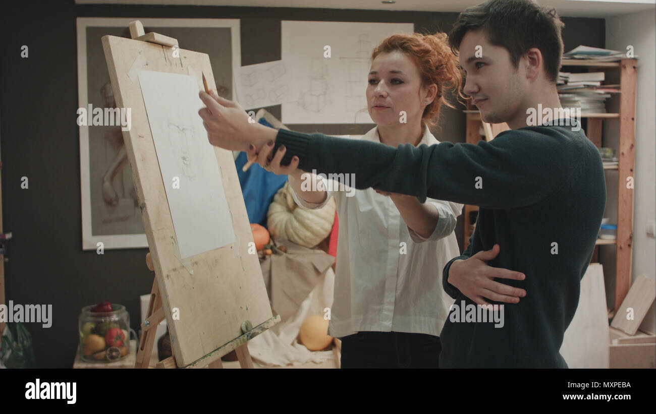 Female painter teaching young man how to draw classical face Stock ...
