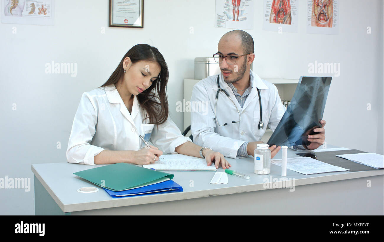 Male doctor teaching his unexperienced female trainee how to analyze ...