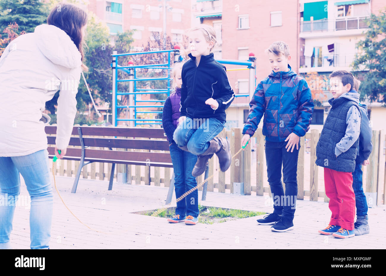 Positive kids playing in jumping rope game in park. Focus on boy Stock ...