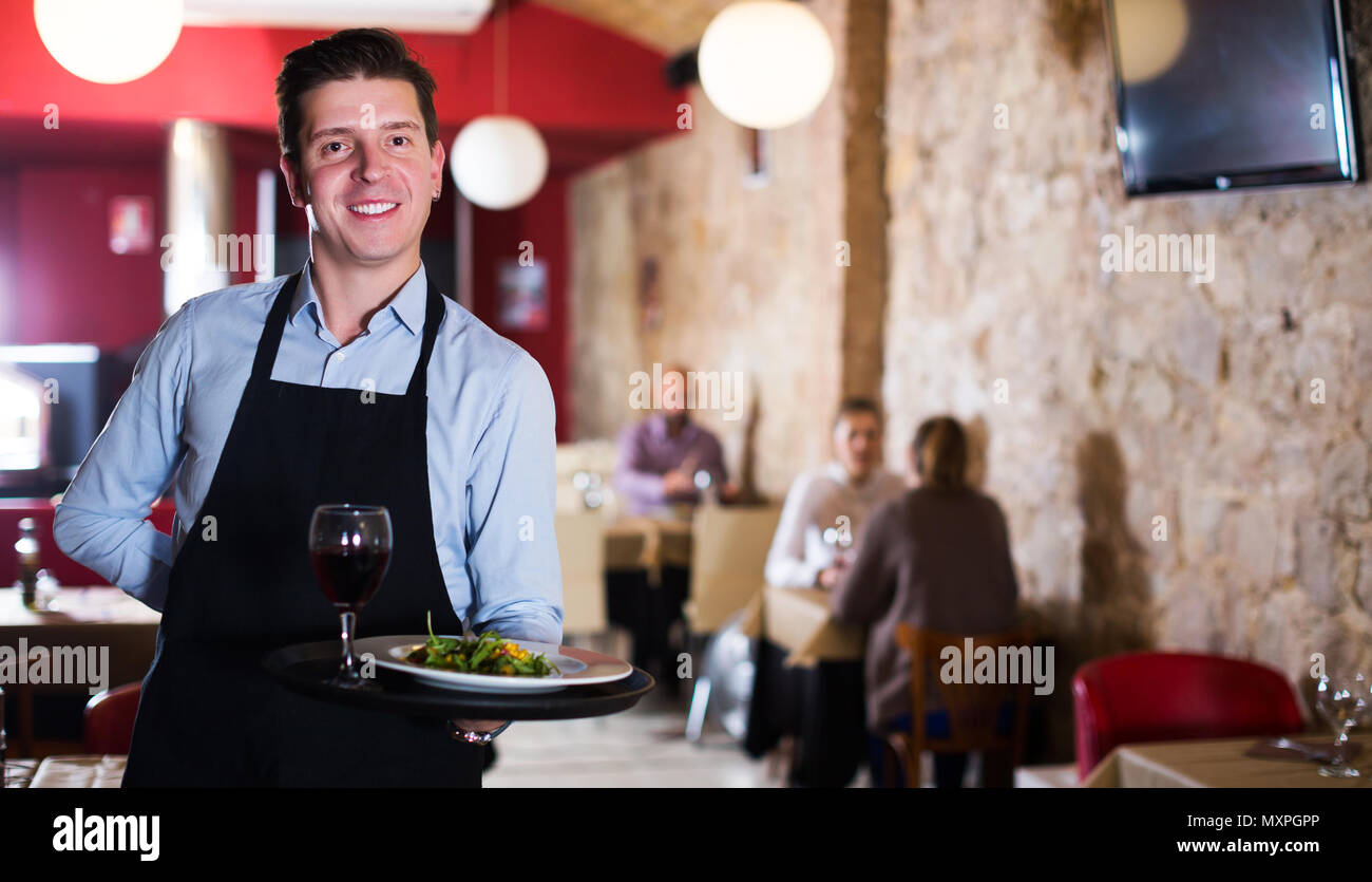 Handsome waiter with serving tray welcoming to restaurant Stock Photo ...