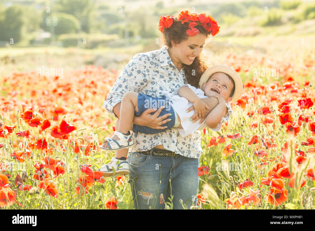 Smiling brunette in a poppy field with her family. Mom and her boy on a ...