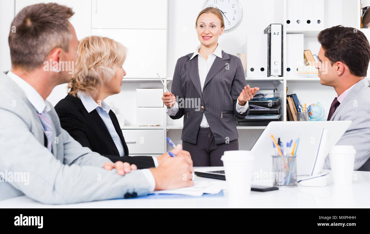 Elegant female chief gathering her managers for meeting at workplace ...