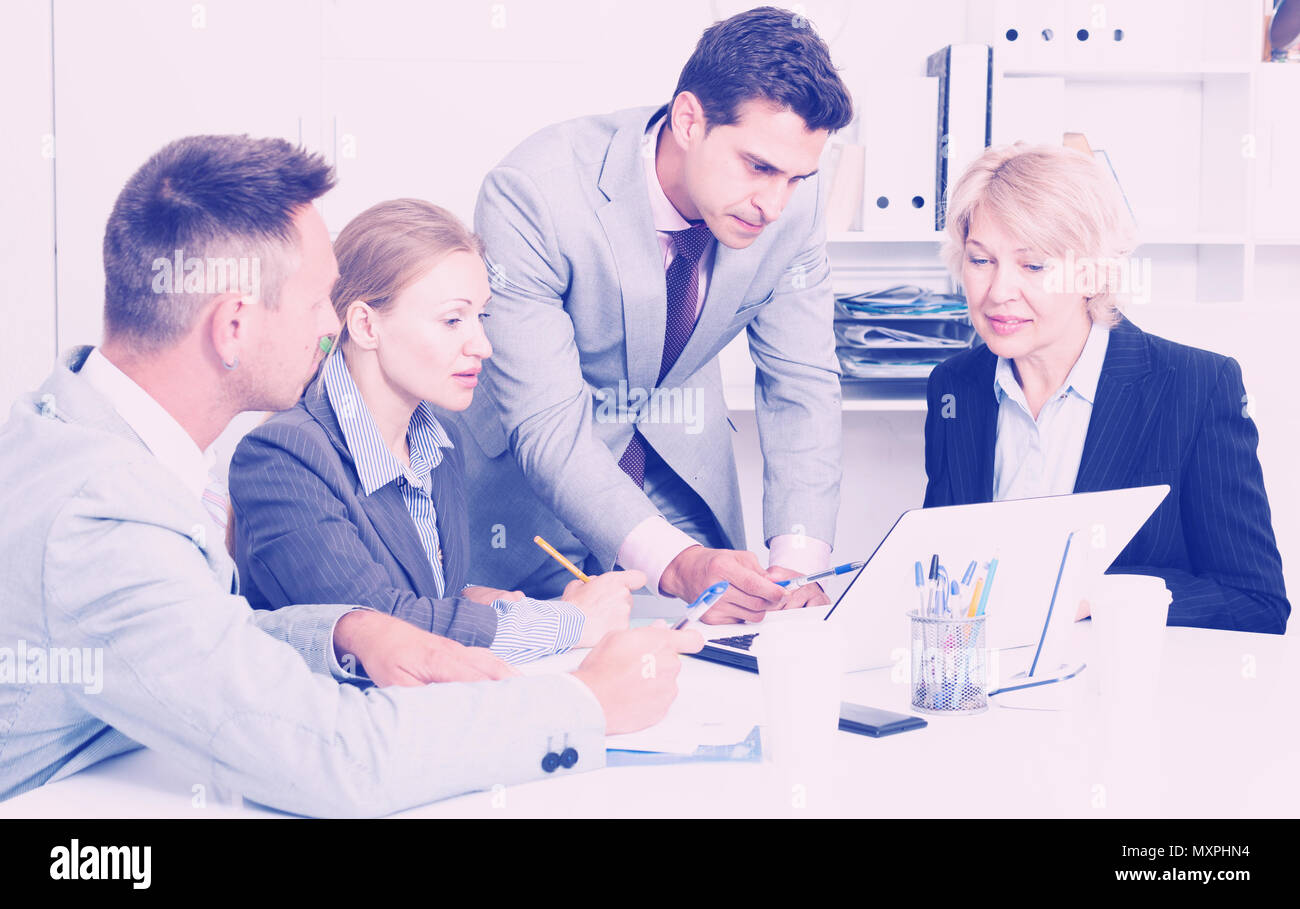 Focused serious business team working with computer in modern office ...