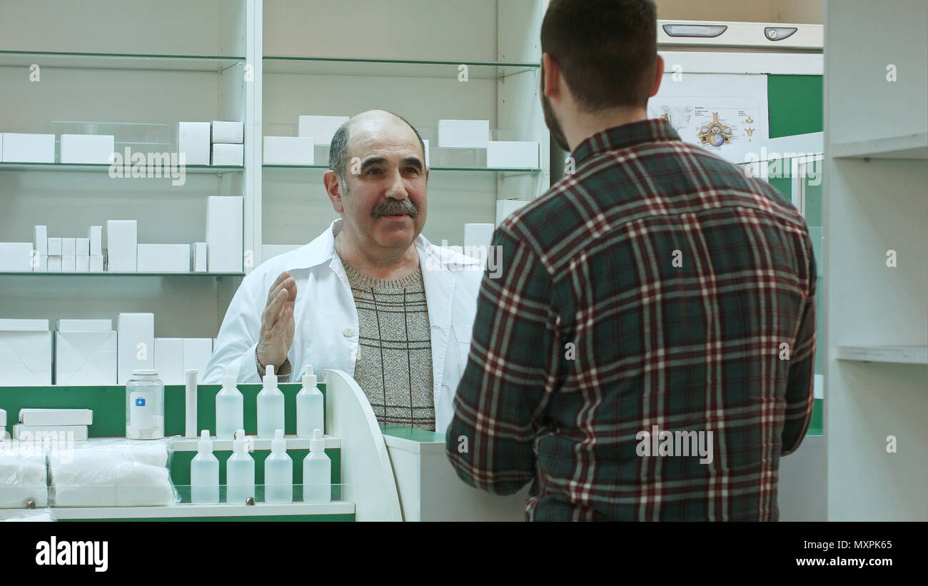 Positive senior druggist giving client medicine at the pharmacy Stock ...