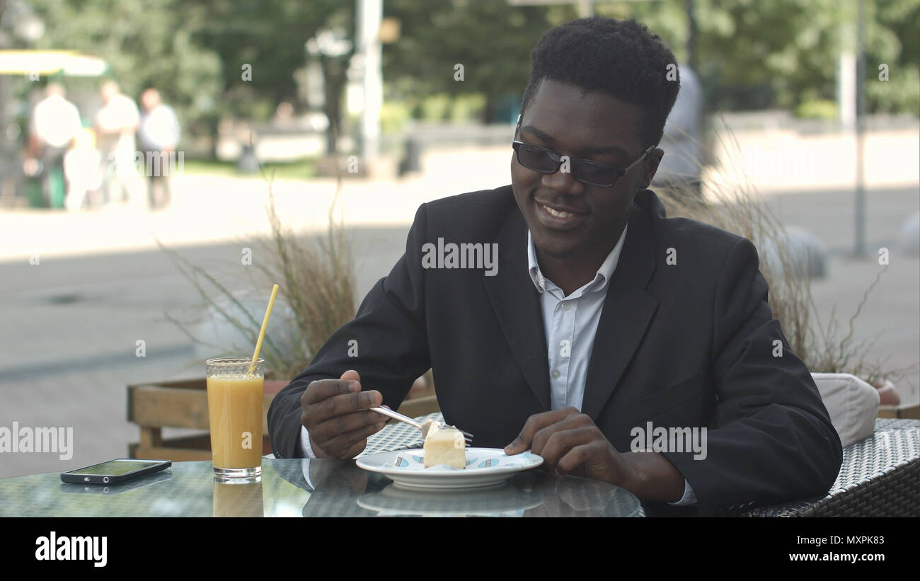 Black waiter serving terrace cafe guests at table Stock Photo - Alamy