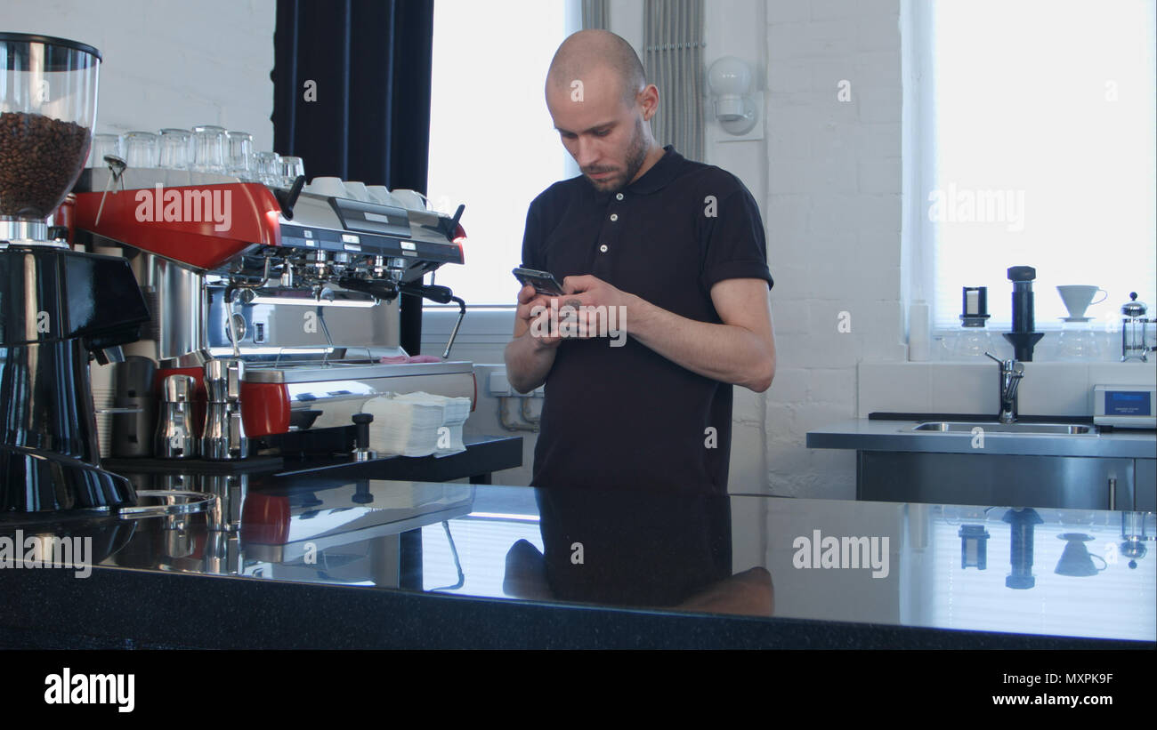 Male barista using smartphone at work place Stock Photo - Alamy