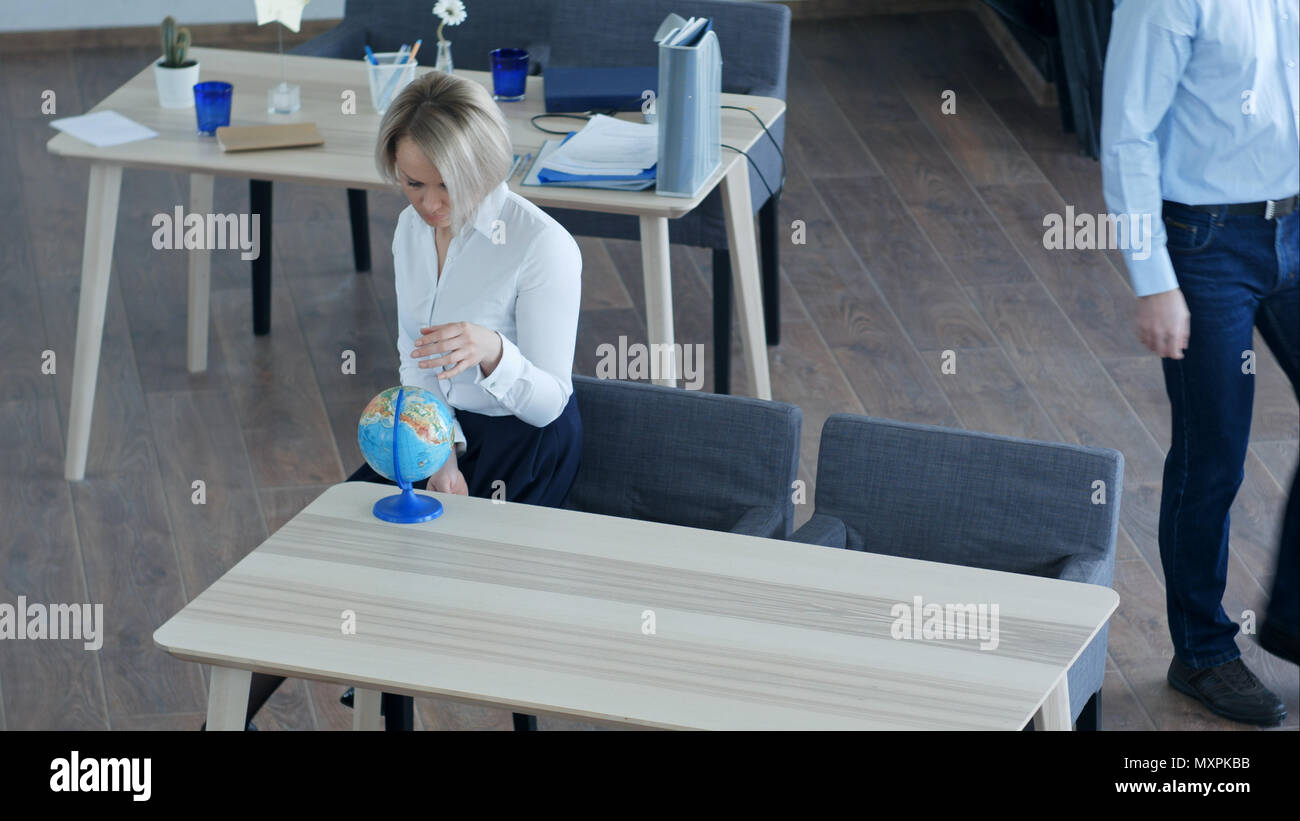 Calm single young woman relaxing at work, looking at globe dreaming ...