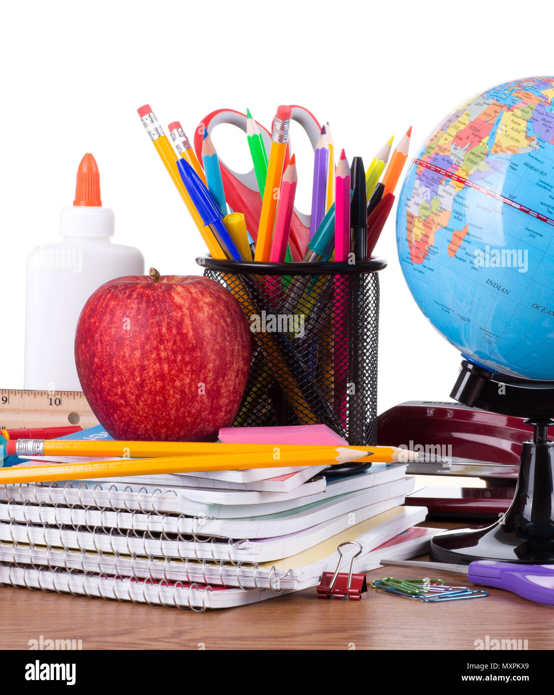 Assortment of school supplies on a wooden desktop and white background ...