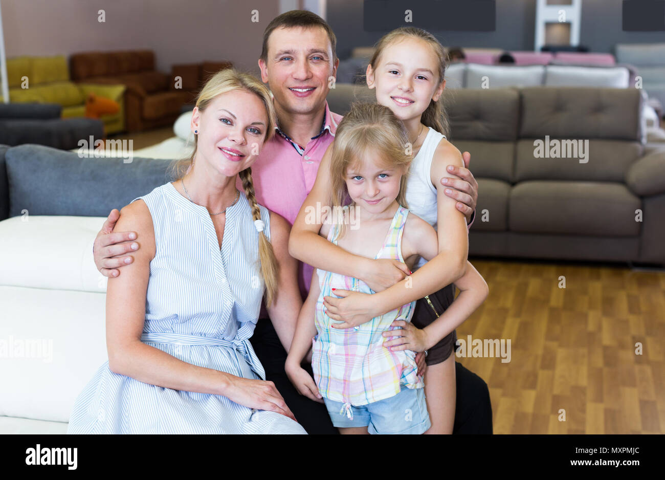 Man and woman with their children are choosing new sofa in furniture ...