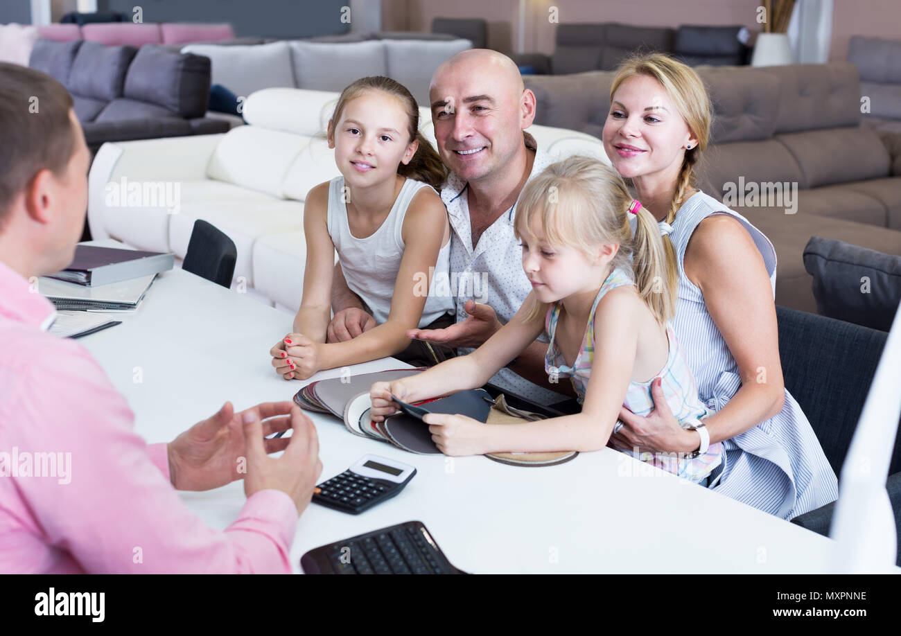 Smiling male with wife and kids consulting with assistant about color ...