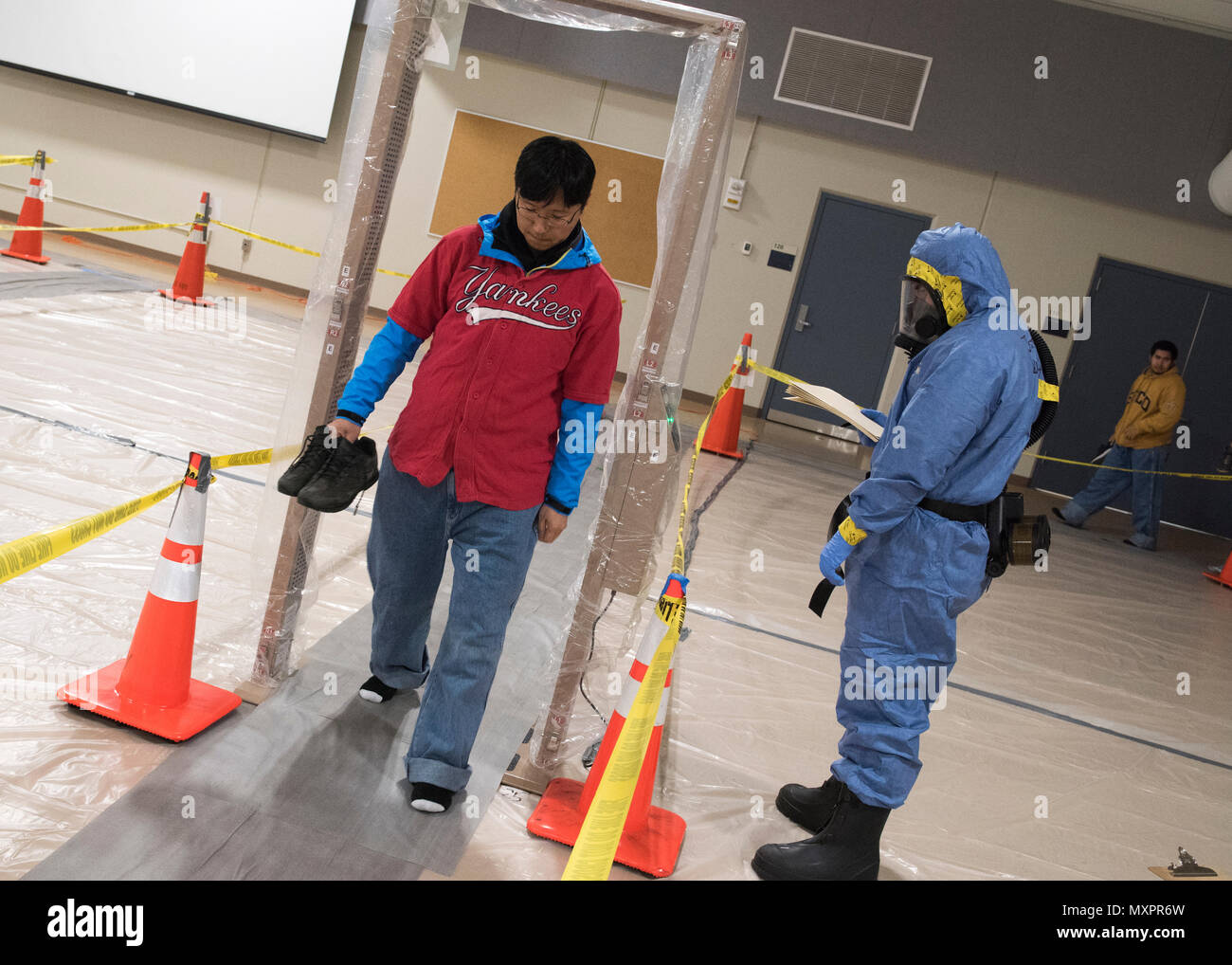 A volunteer walks through a radiation detector while a member of the ...