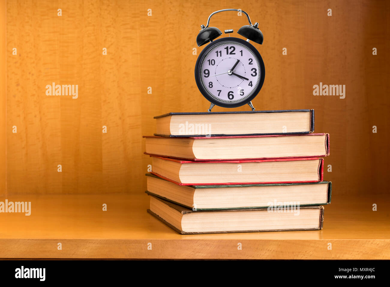 Book and alarm clock on the table in the classroom Stock Photo - Alamy