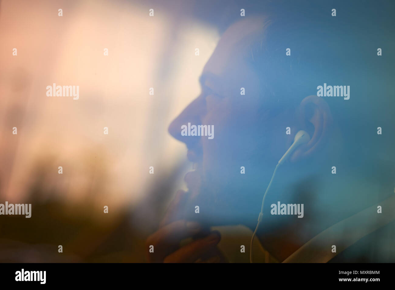 Close up through a window of a business man wearing ear buds talking on ...