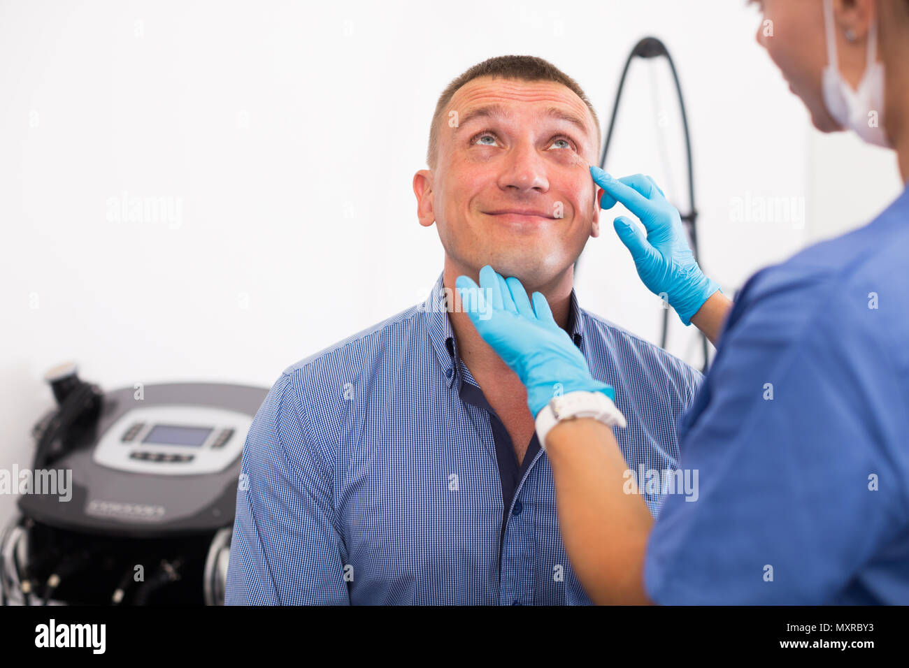 Female doctor is examining face of client after procedure in cabinet ...