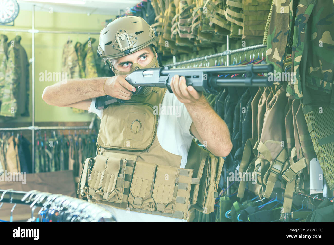 Young guy in military equipment with gun in airsoft shop Stock Photo ...