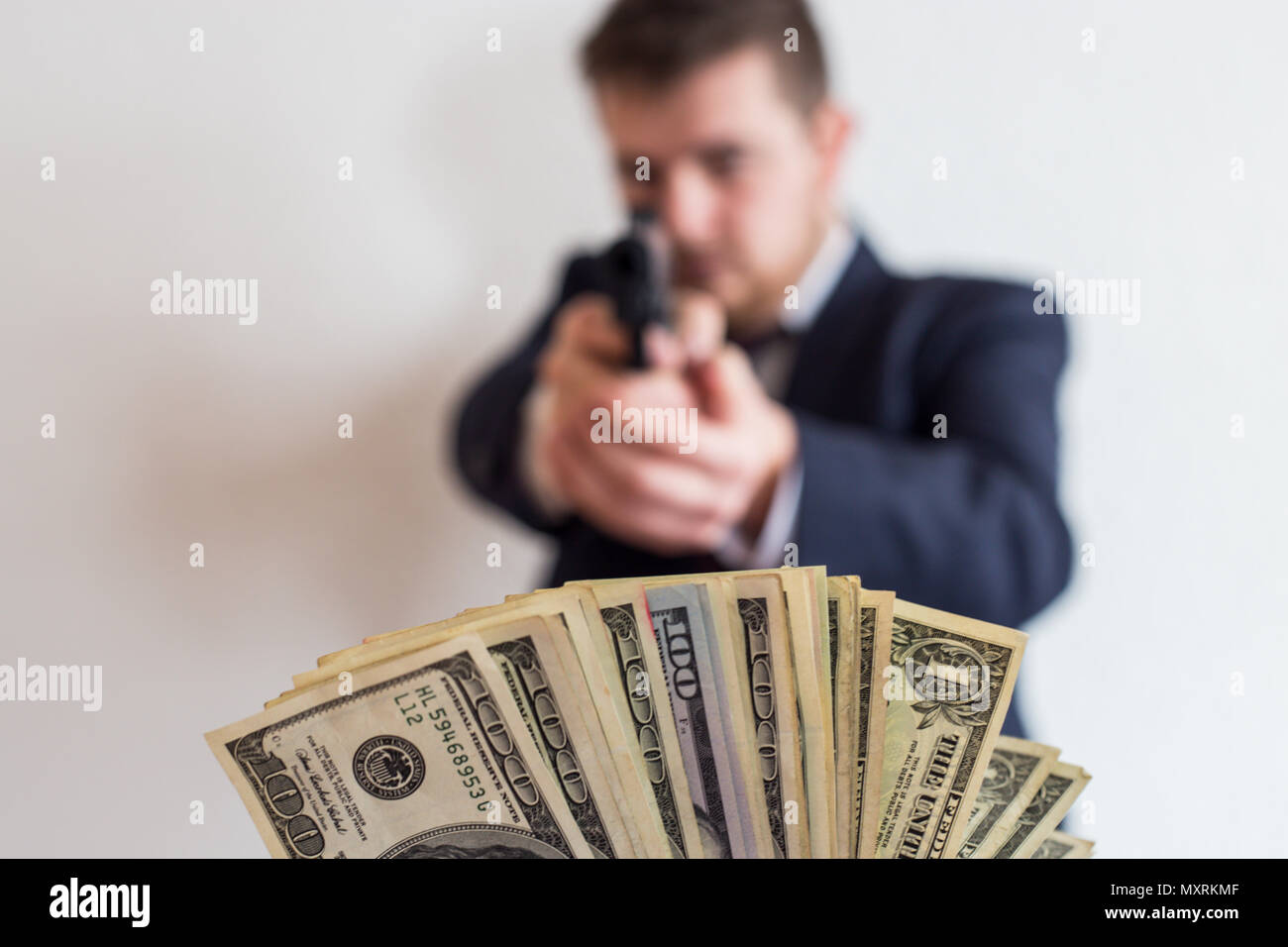 A thief in a suit with a gun directed at a man takes cash, hundreds of ...