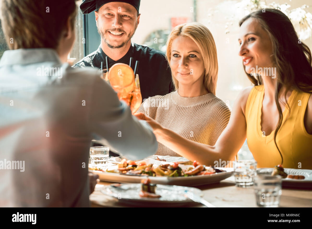 Experienced chef congratulated by four people at a trendy restaurant ...