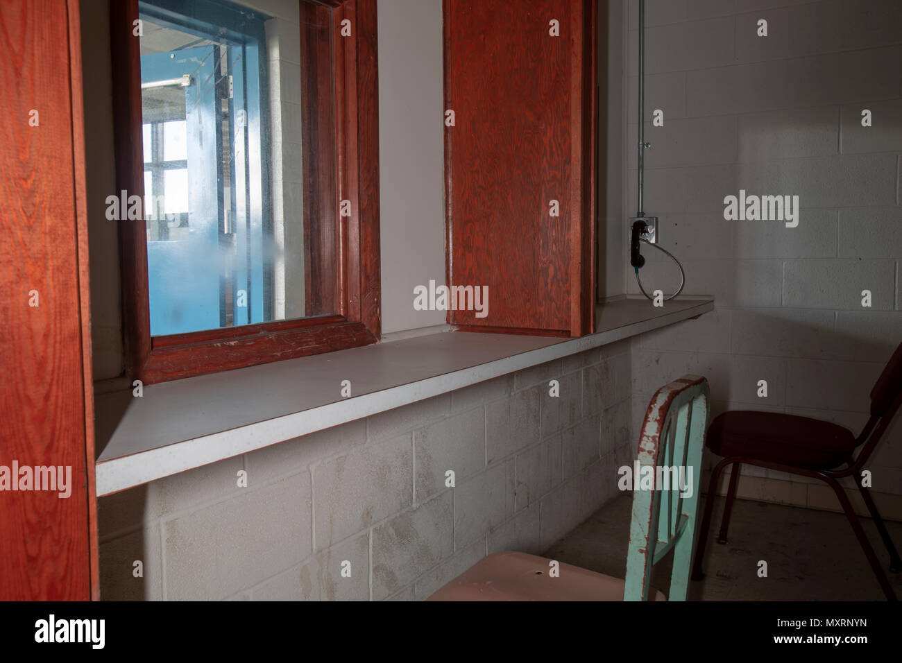 Empty chairs inside prison visitation phone windows Stock Photo - Alamy