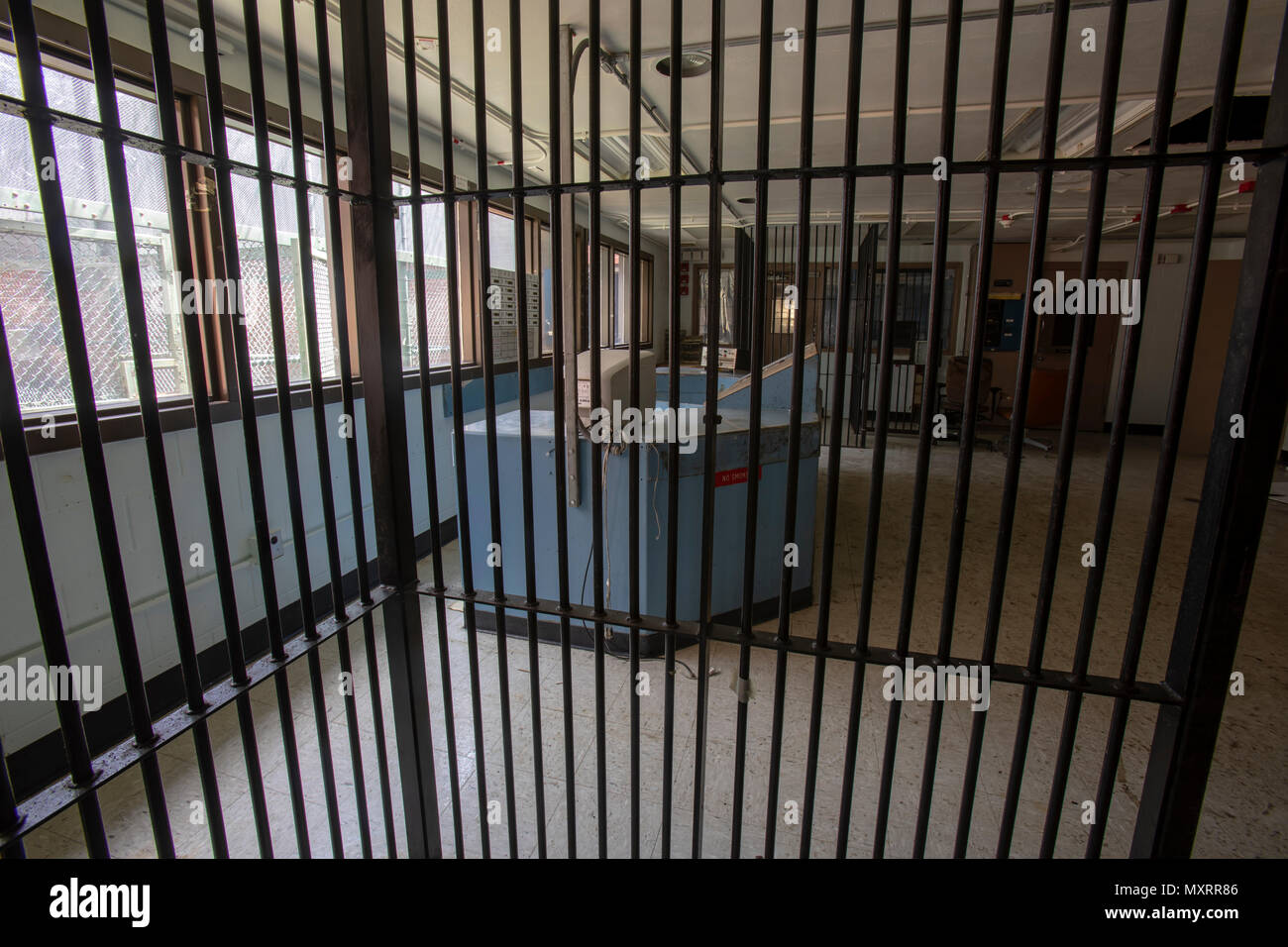 Guard desk behind bars inside prison cellblock with exercise pens ...